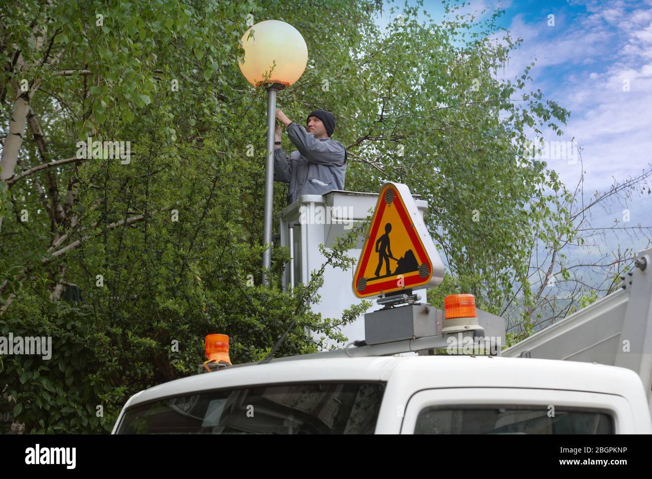 Worker in lift bucket repair street light. People change the lamp on a ...