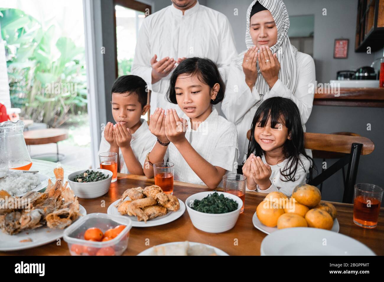 muslim family praying before eating their food. breaking the fast or ...