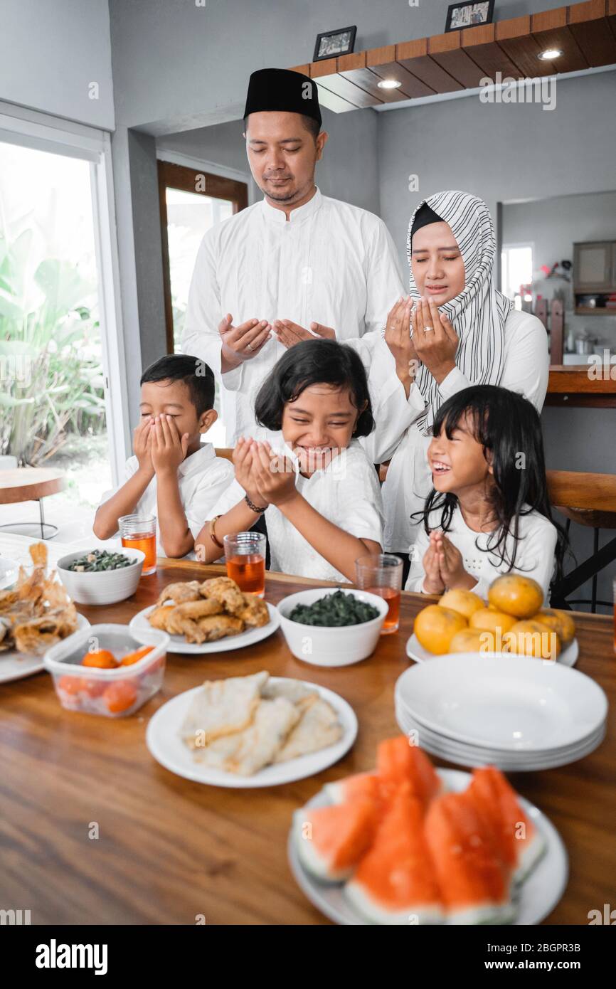 muslim family praying before eating their food. breaking the fast or ...