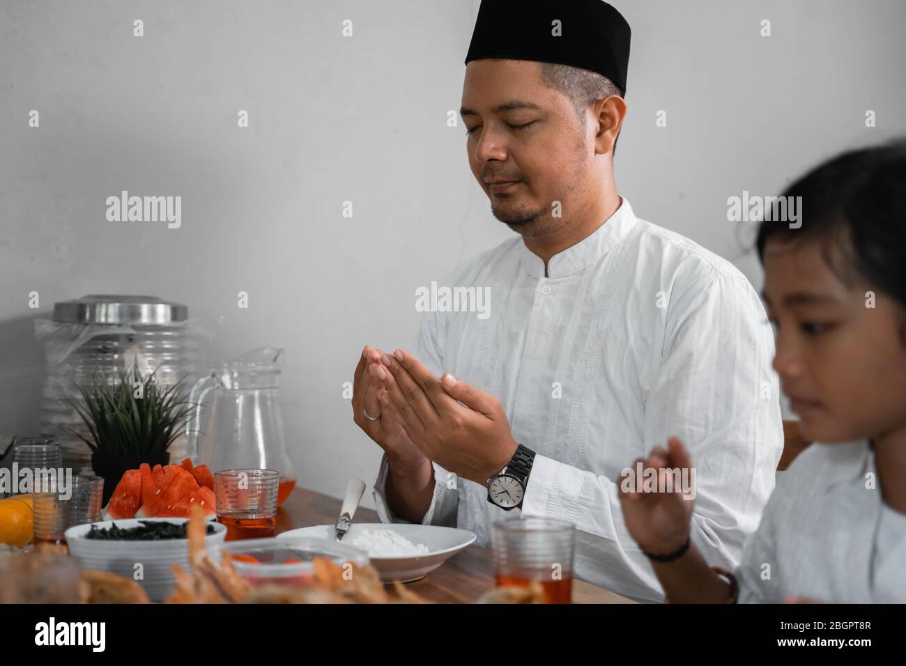 muslim family praying before eating their food. breaking the fast or ...
