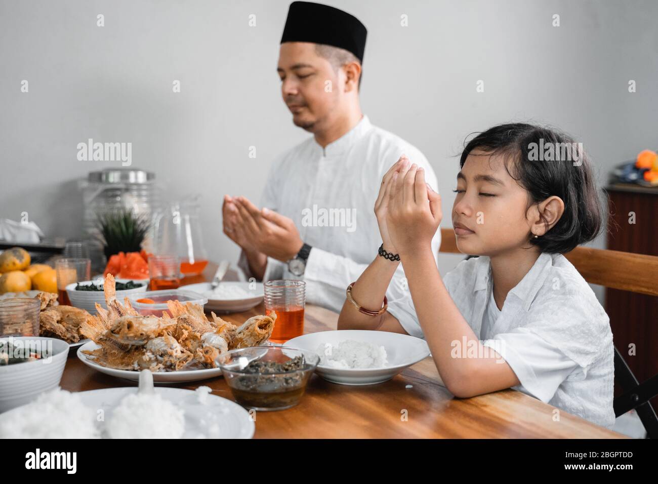 muslim family praying before eating their food. breaking the fast or ...