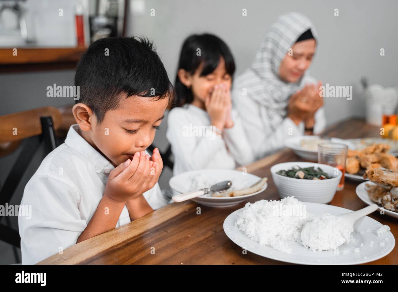 muslim family praying before eating their food. breaking the fast or ...
