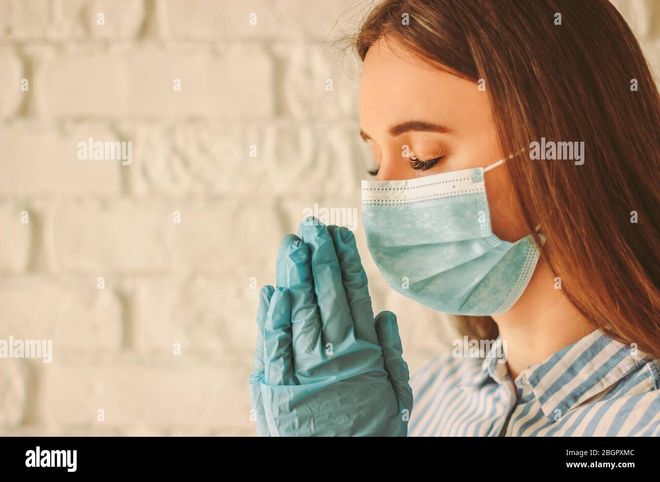 Religious catholic girl in medical face mask and protective gloves ...