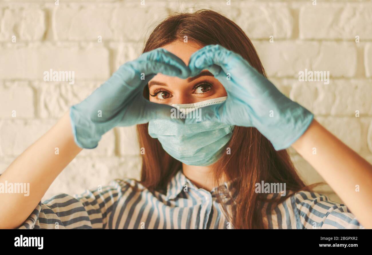 Happy girl in medical face mask and protective gloves looks through ...