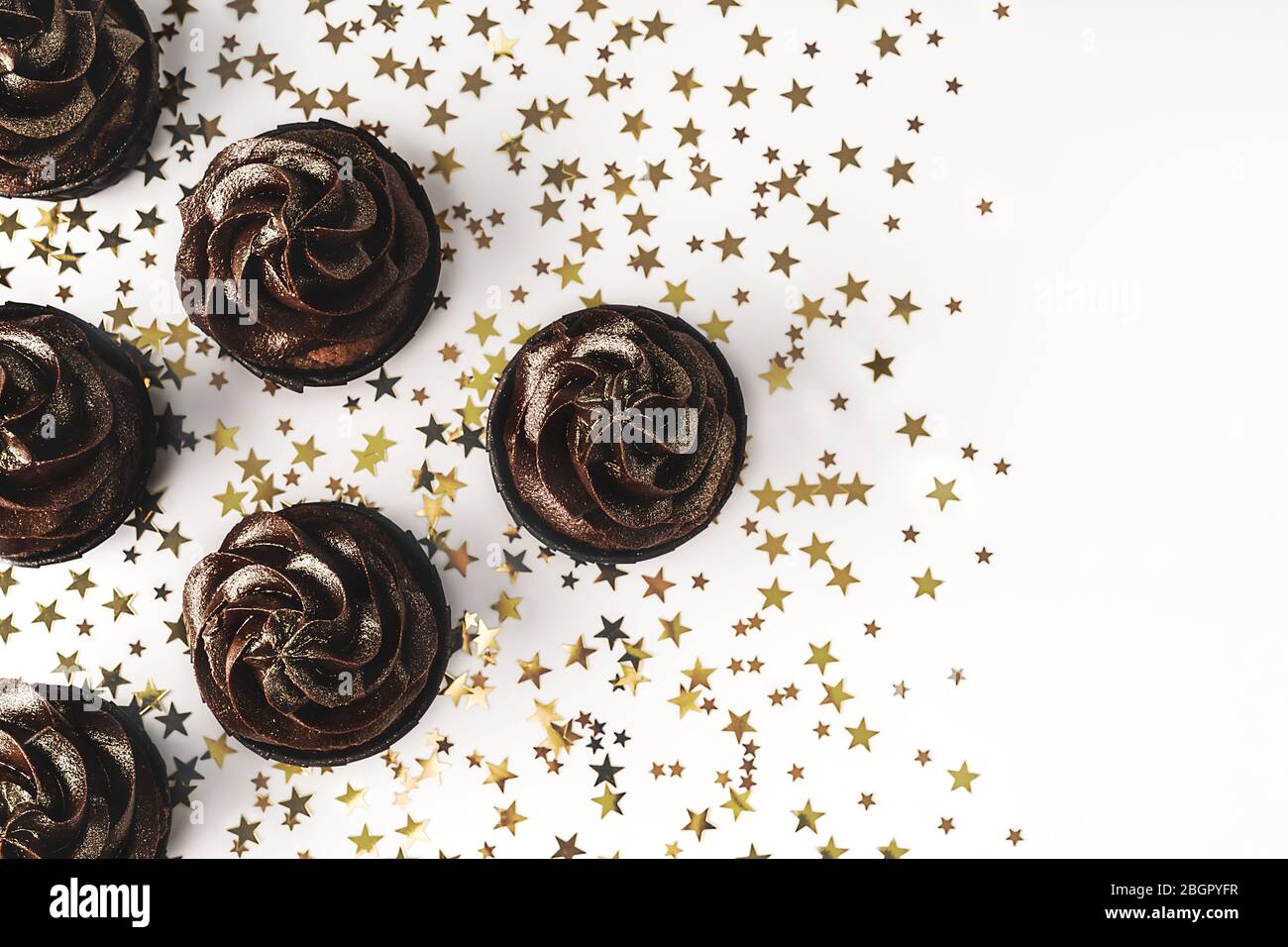 Chocolate cupcakes with chocolate icing and sprinkled gold sparkles on ...