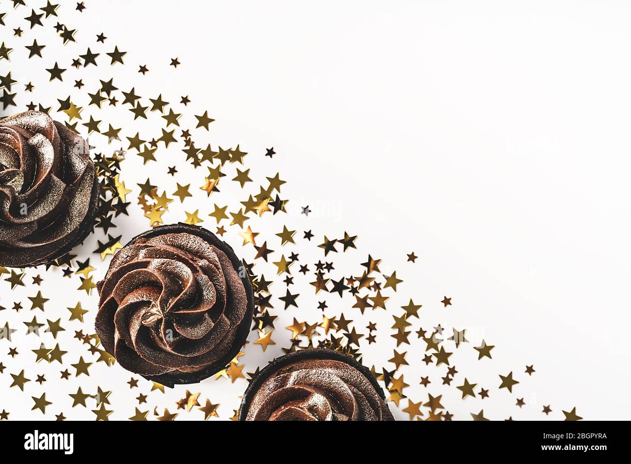 Chocolate cupcakes with chocolate icing and sprinkled gold sparkles on ...