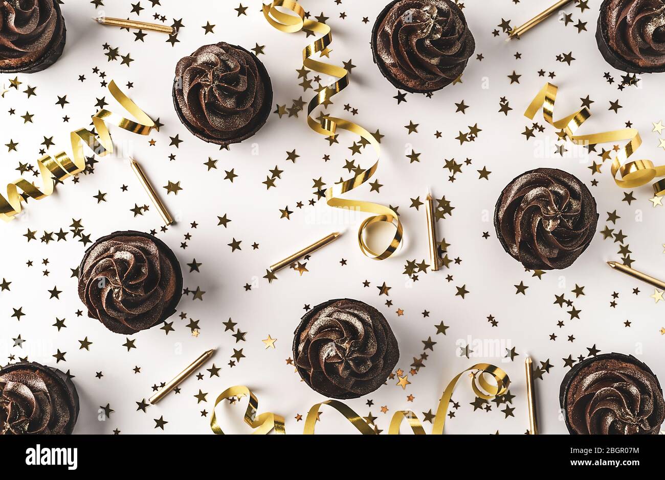 Chocolate cupcakes with chocolate icing and sprinkled gold sparkles on ...
