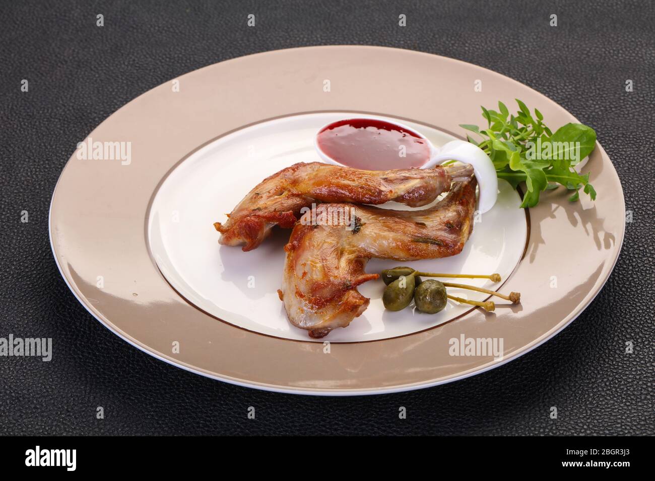 Roasted rabbit legs with cowberry sauce Stock Photo - Alamy