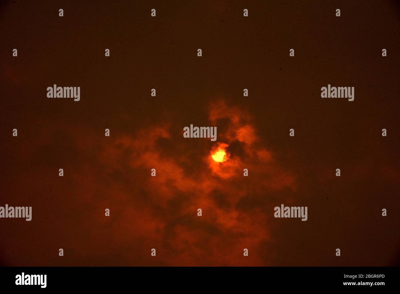 The sun, filtered orange by haze from forest fires, glows behind ...