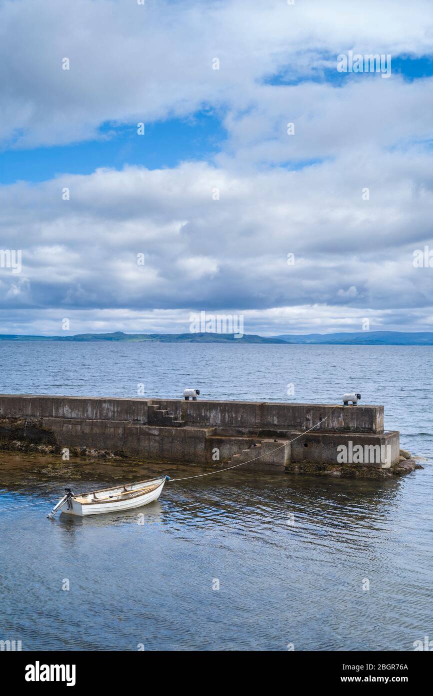 Rowing boat moored to a sheep shape bollard on the seawall in harbour ...