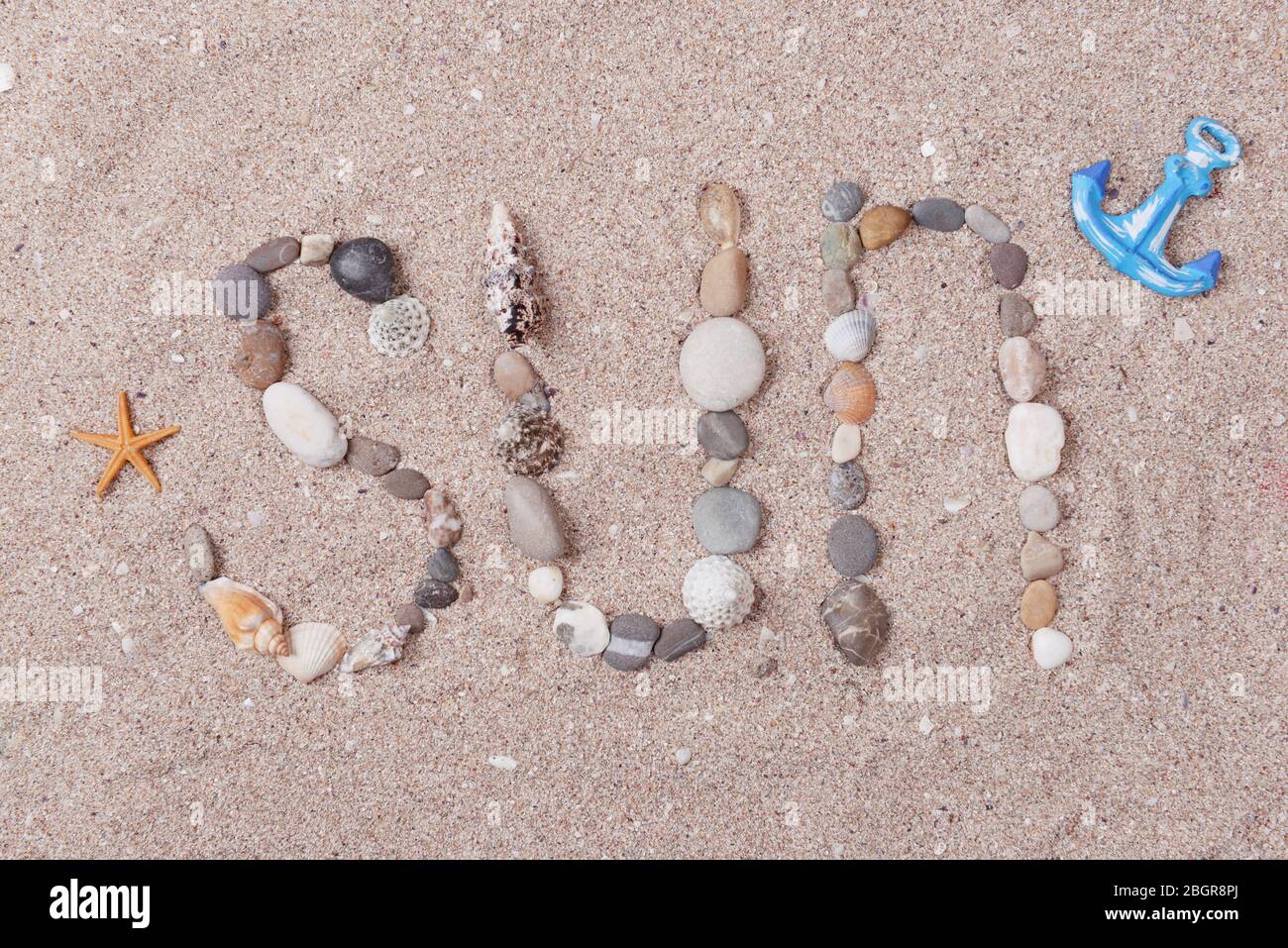 Word sun made from sea shells and stones on sand Stock Photo - Alamy