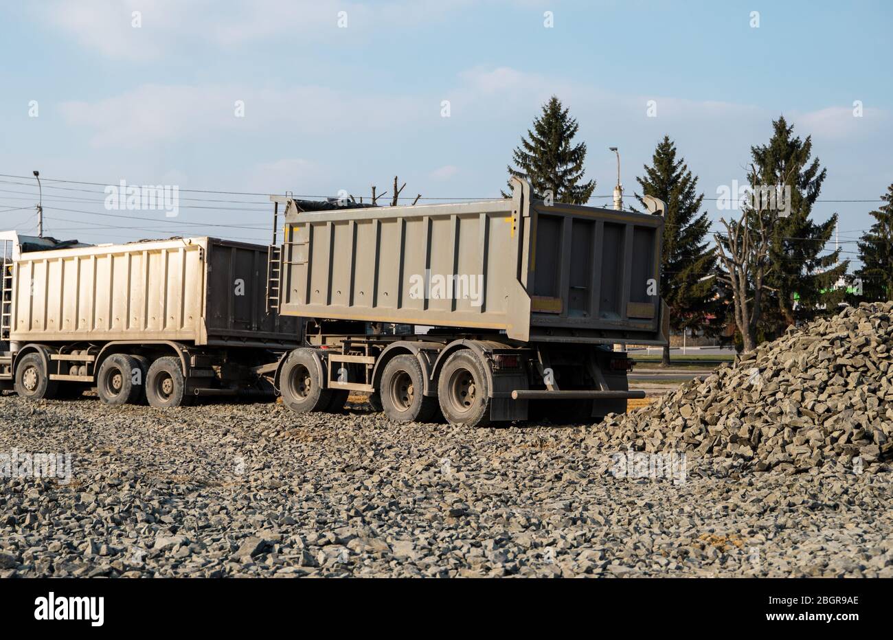 A dump truck is dumping gravel on a construction site. Dump truck dumps ...