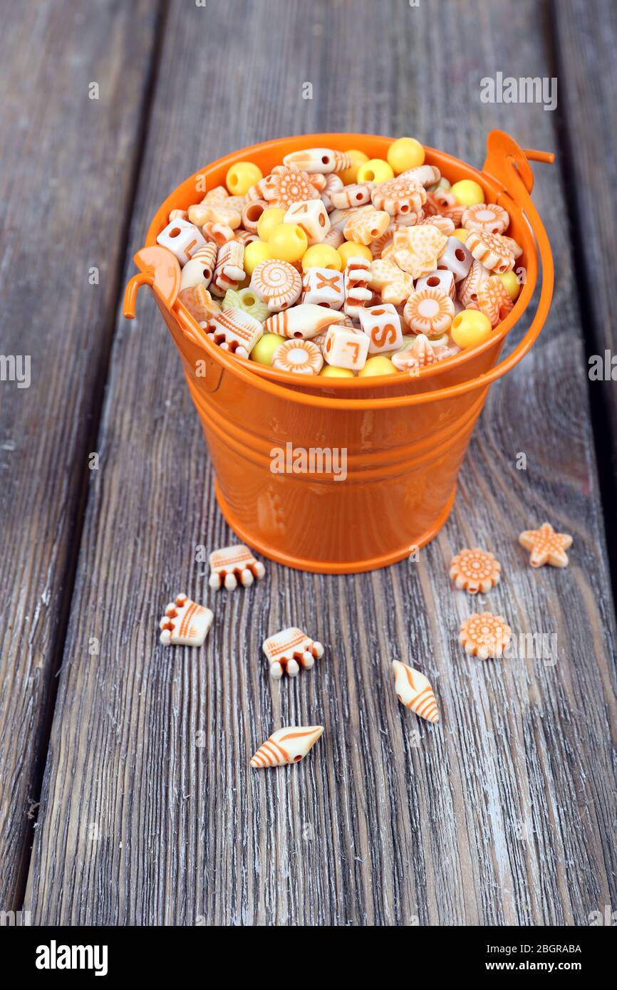 Beads in metal bucket on wooden background Stock Photo - Alamy