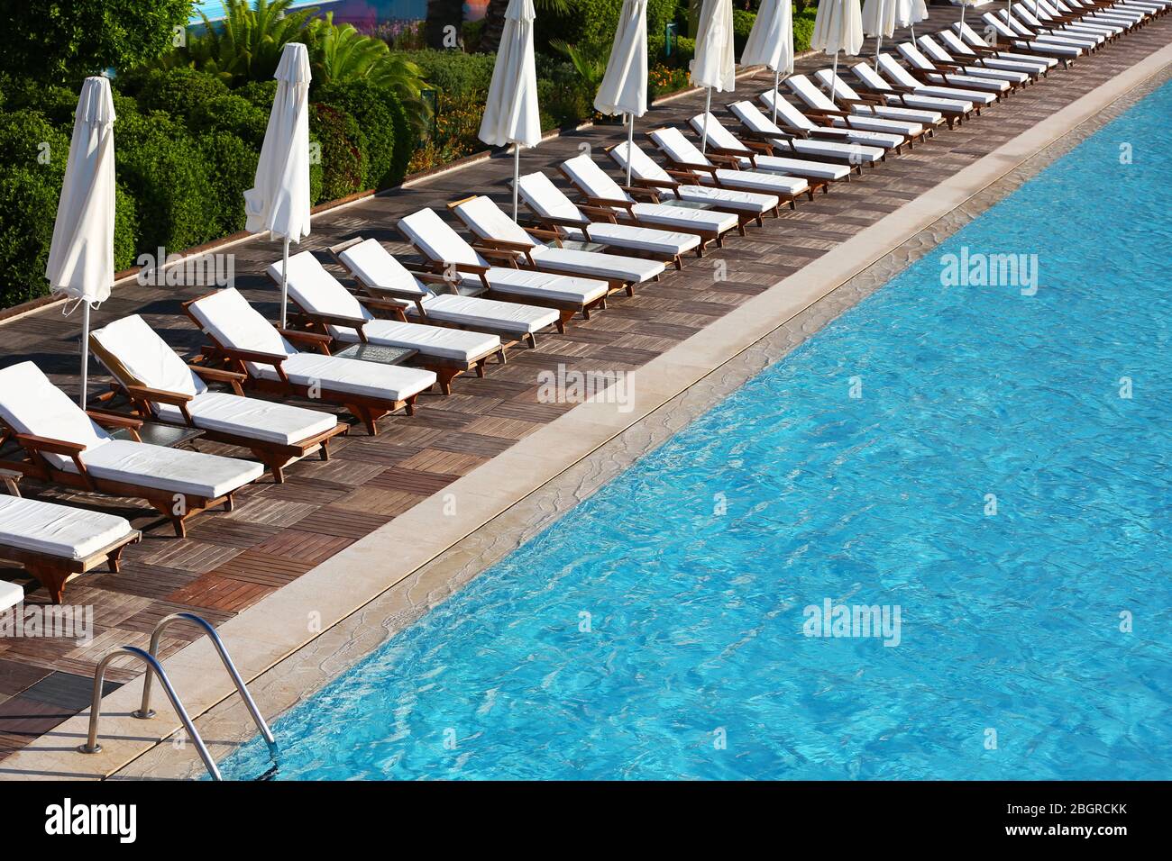 Lounge sunbeds near swimming pool Stock Photo - Alamy