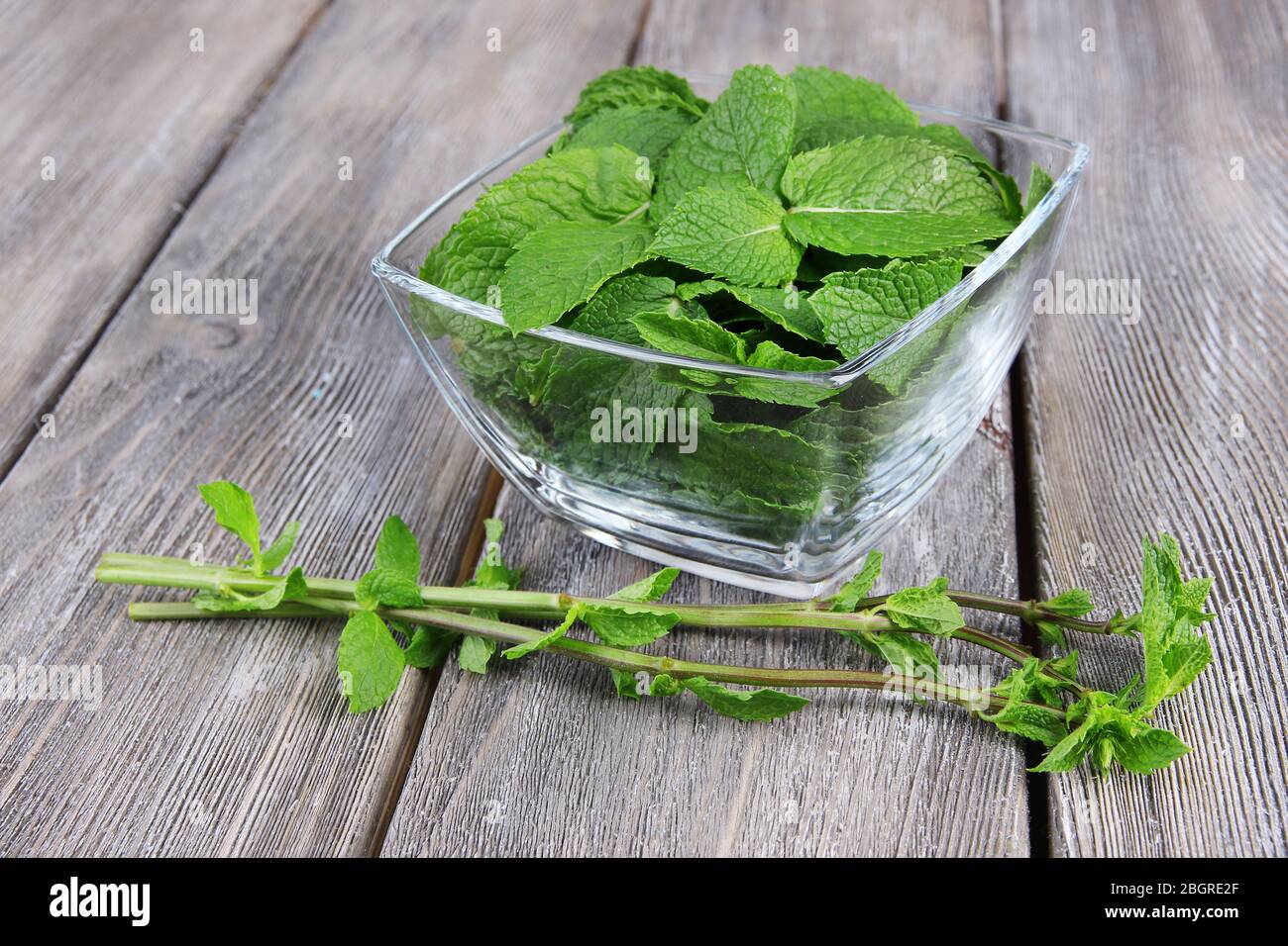 Glass square bowl of mint leaves on wooden background Stock Photo - Alamy