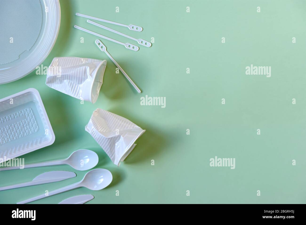 Two smashed white plastic coffee cups, spoons, knives, stirrers, plate ...