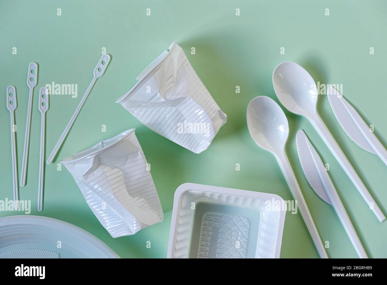 Two smashed white plastic coffee cups, spoons, knives, stirrers, plate ...