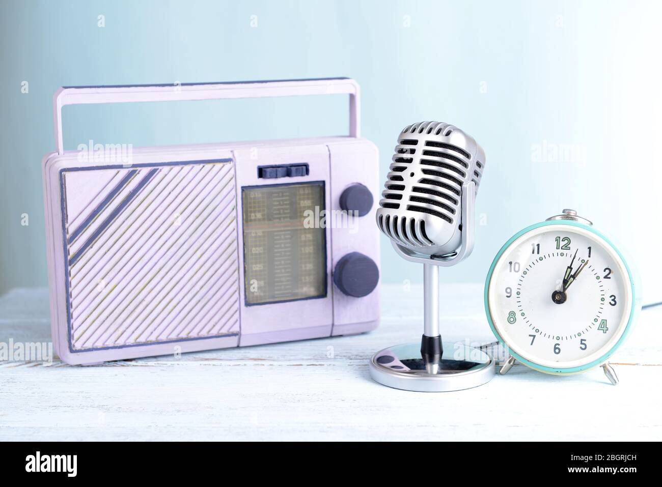 Vintage microphone,alarm clock and radio on table on light blue ...