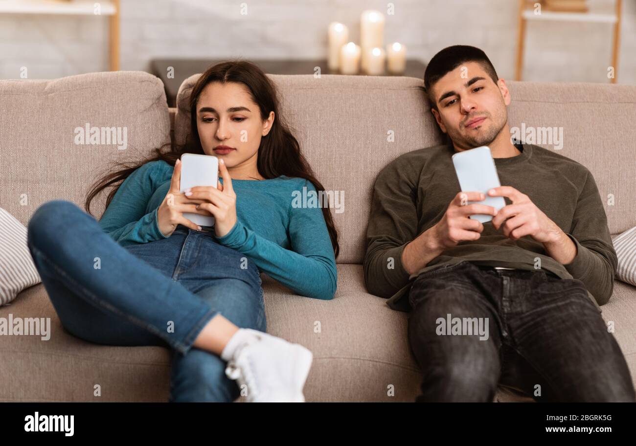 Couple using cell phones sitting on the couch Stock Photo - Alamy