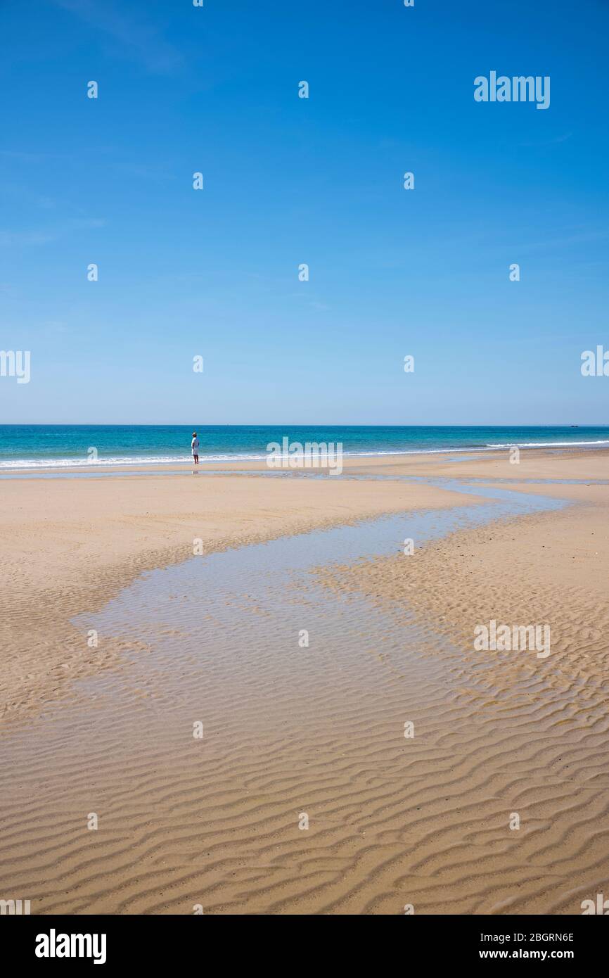 Lone figure of holidaymaker on sandy beach with ripples in the sand ...