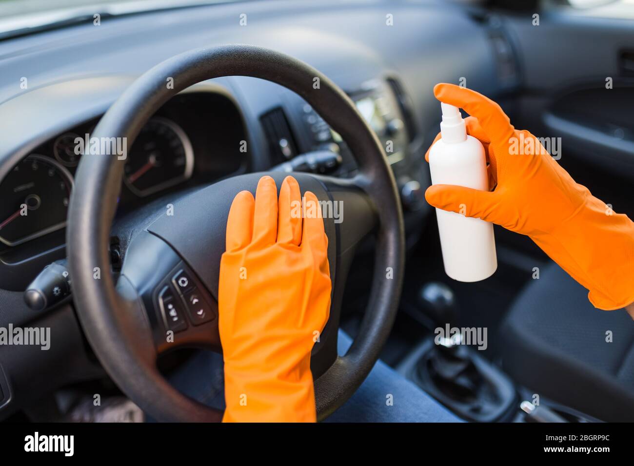 Driver holding bottle spray of sanitizer to protect car steering wheel ...