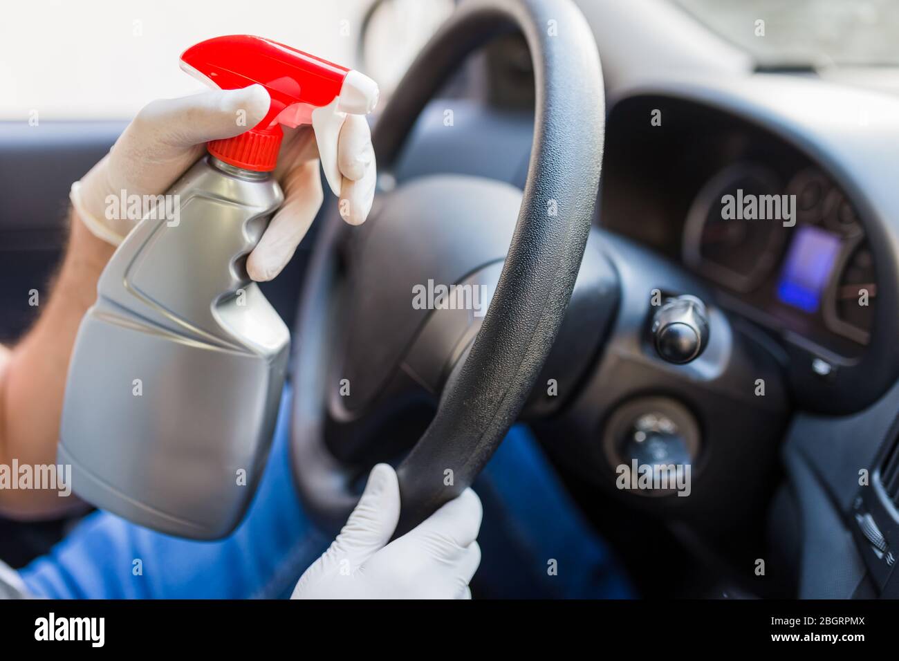 Driver wearing protective gloves and spraying disinfectant on car ...