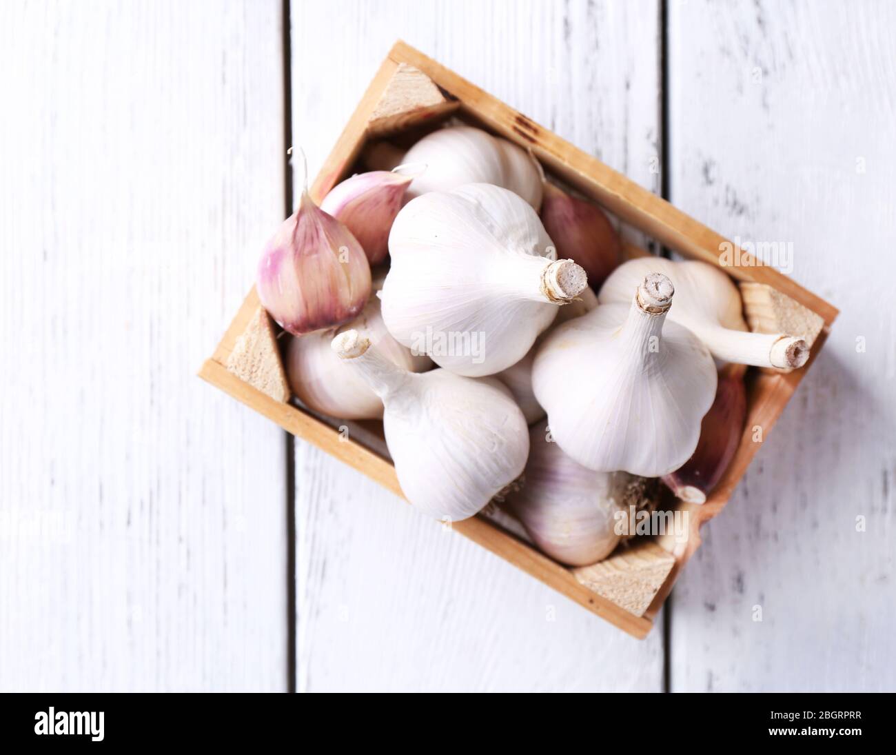 Fresh garlic in box, on wooden background Stock Photo - Alamy