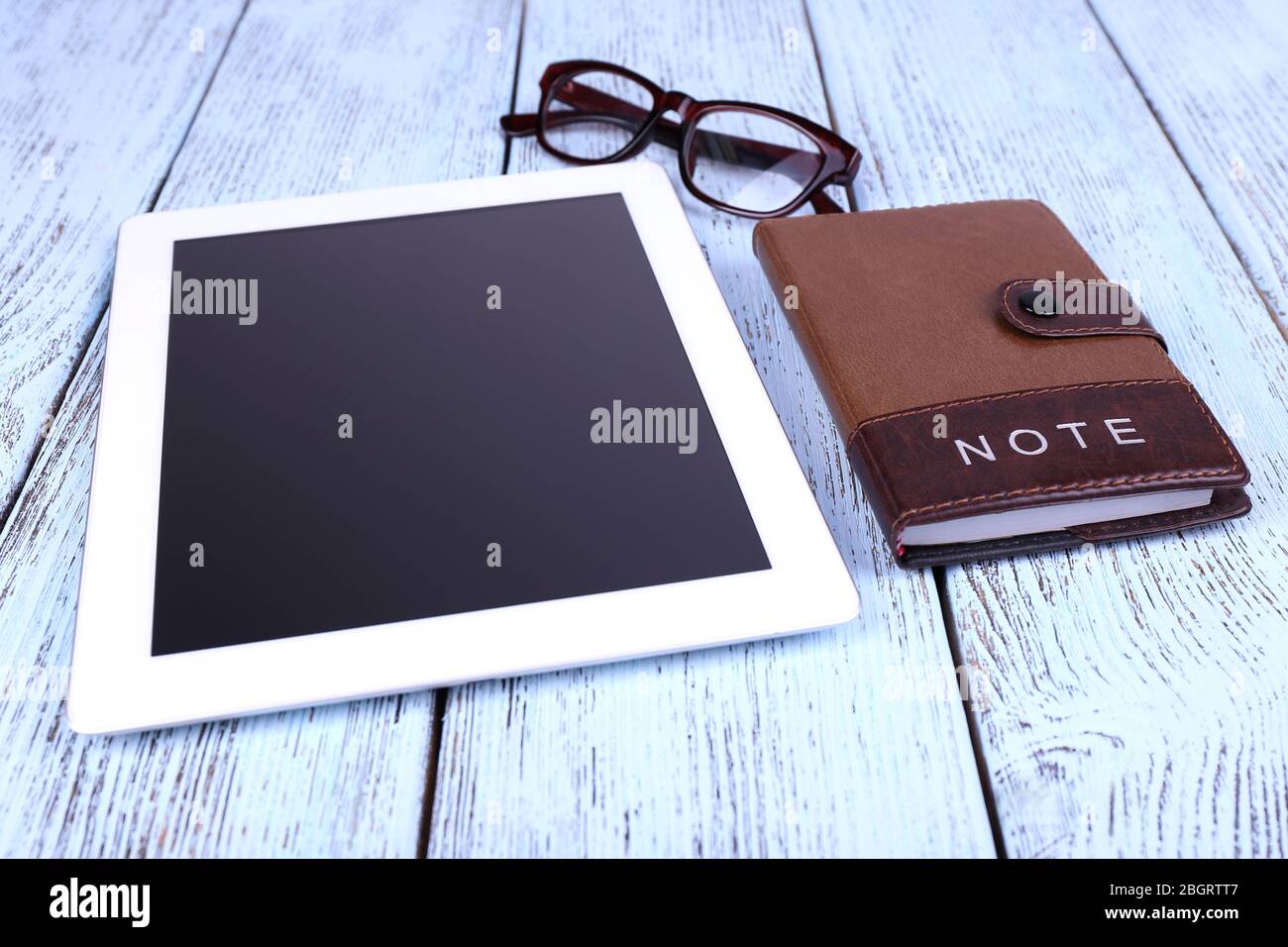 Tablet, notebook and glasses on wooden background Stock Photo - Alamy