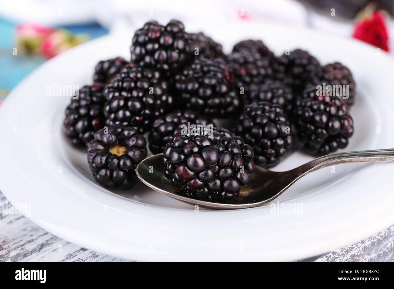 Sweet blackberries on plate, on color wooden background Stock Photo - Alamy