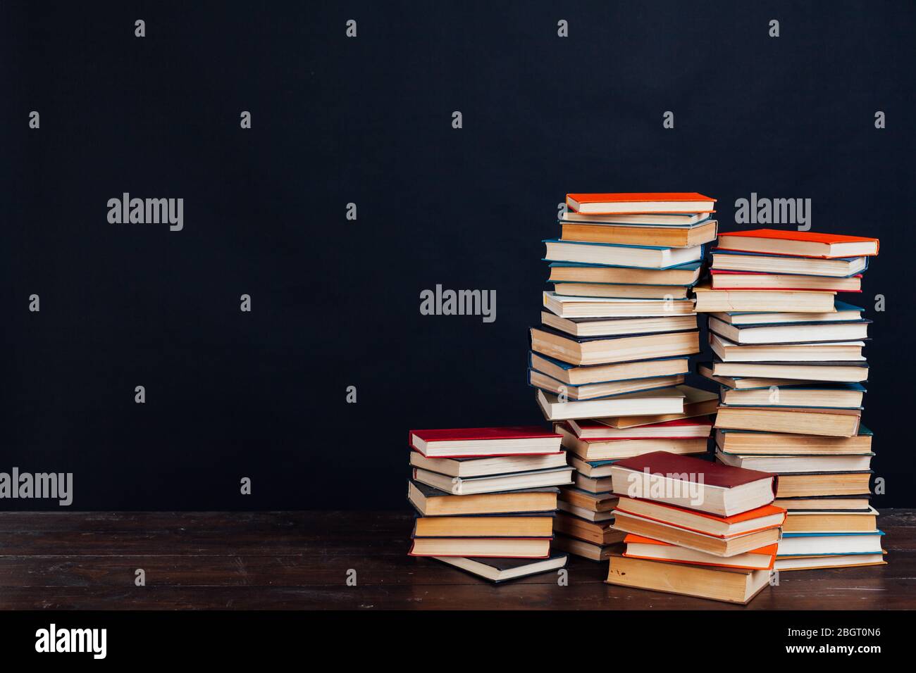 many stacks of educational books in the university library on a black ...