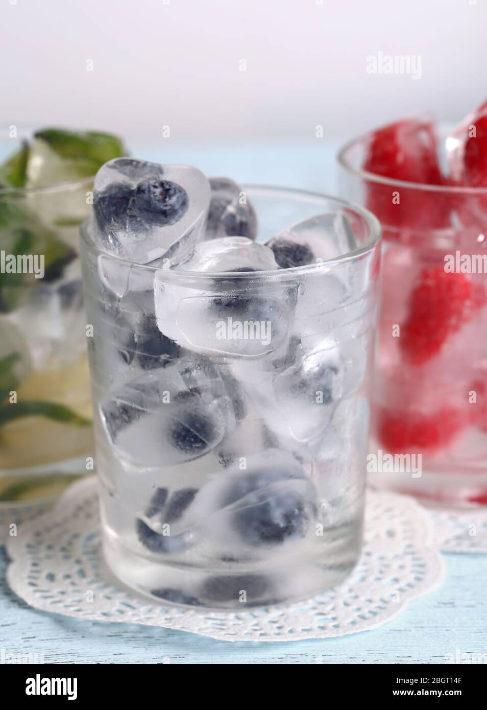 Ice cubes with mint leaves, raspberry and blueberry in glasses, on ...
