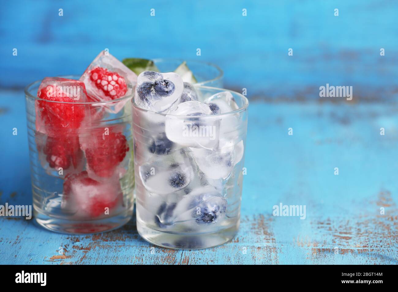 Ice cubes with mint leaves, raspberry and blueberry in glasses, on ...
