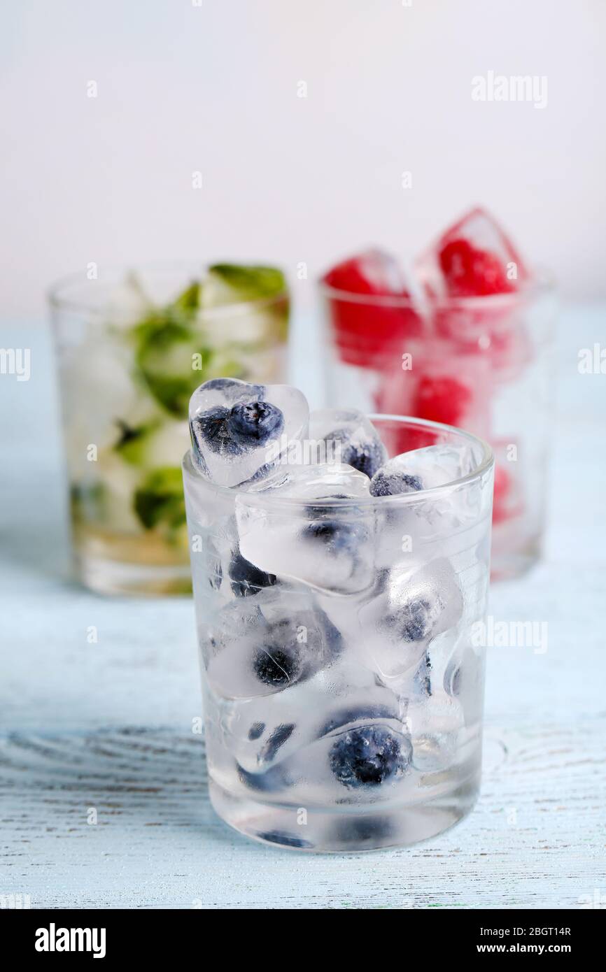 Ice cubes with mint leaves, raspberry and blueberry in glasses, on ...