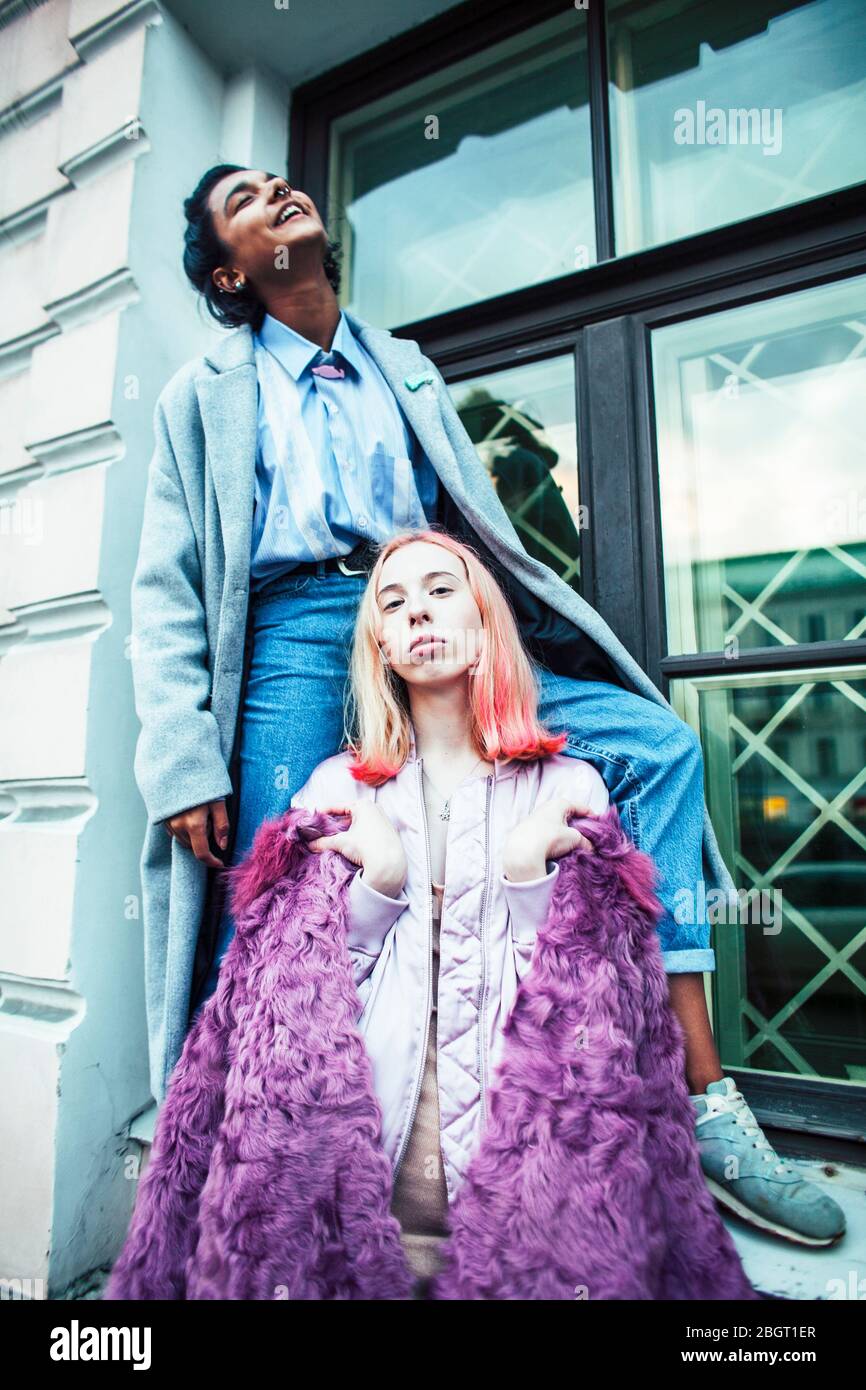 Two teenage girls infront of university building smiling, having fun ...