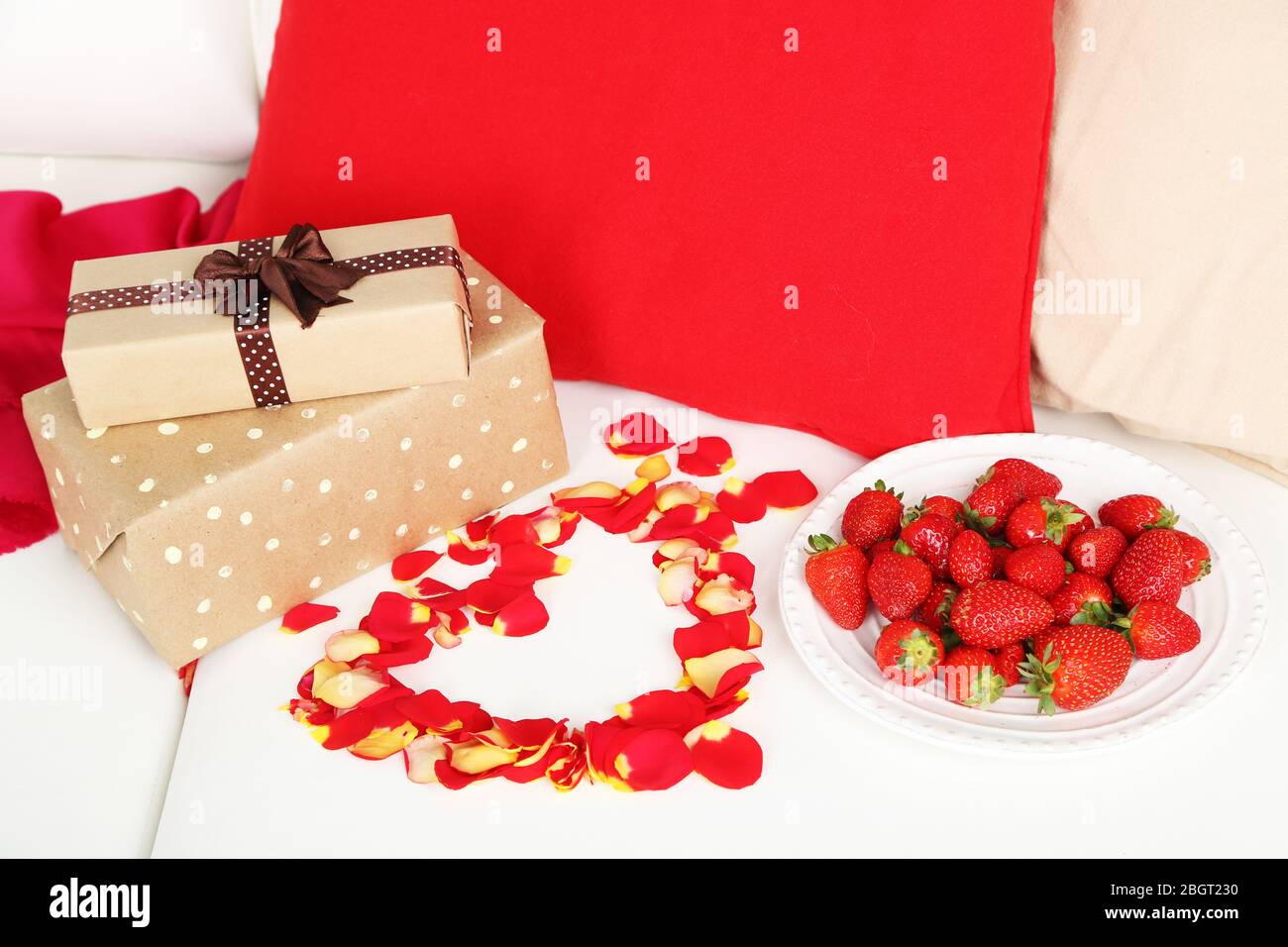 Romantic still life with strawberry, gifts and petals of roses on sofa ...