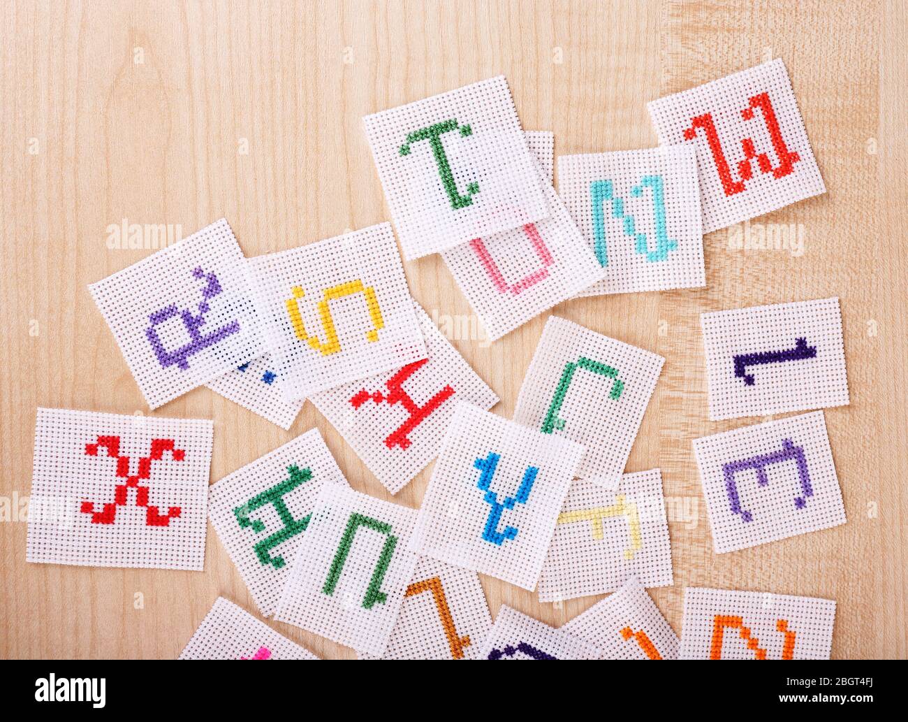 Handmade embroidered letters on white fabric, on wooden background ...
