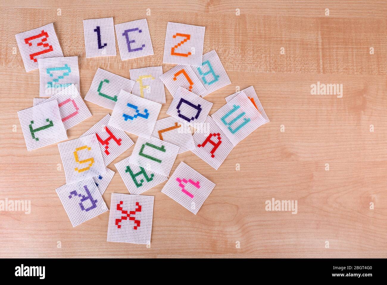 Handmade embroidered letters on white fabric, on wooden background ...
