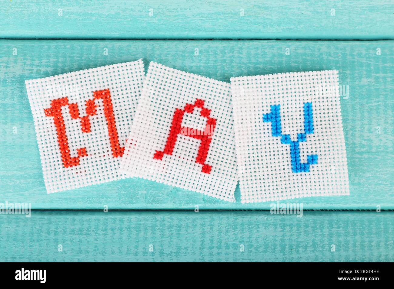 Word made embroidered letters on white fabric, on wooden background ...
