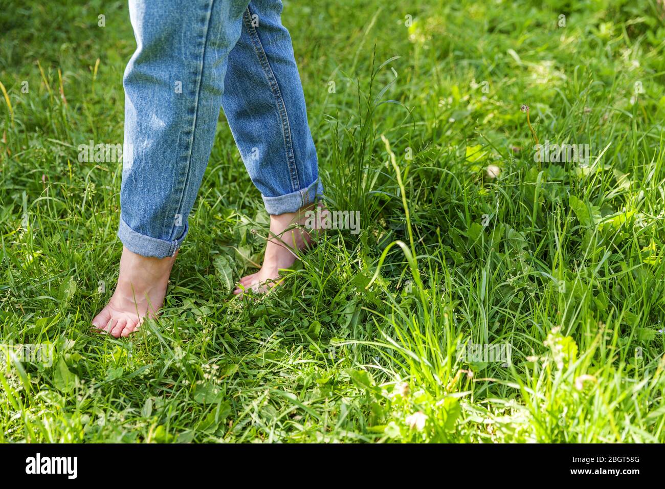 Two beautiful female feet walking on grass in sunny summer morning ...