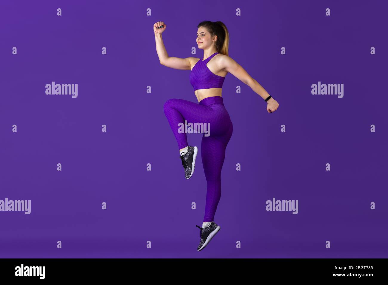 In jump. Beautiful young female athlete practicing in studio ...