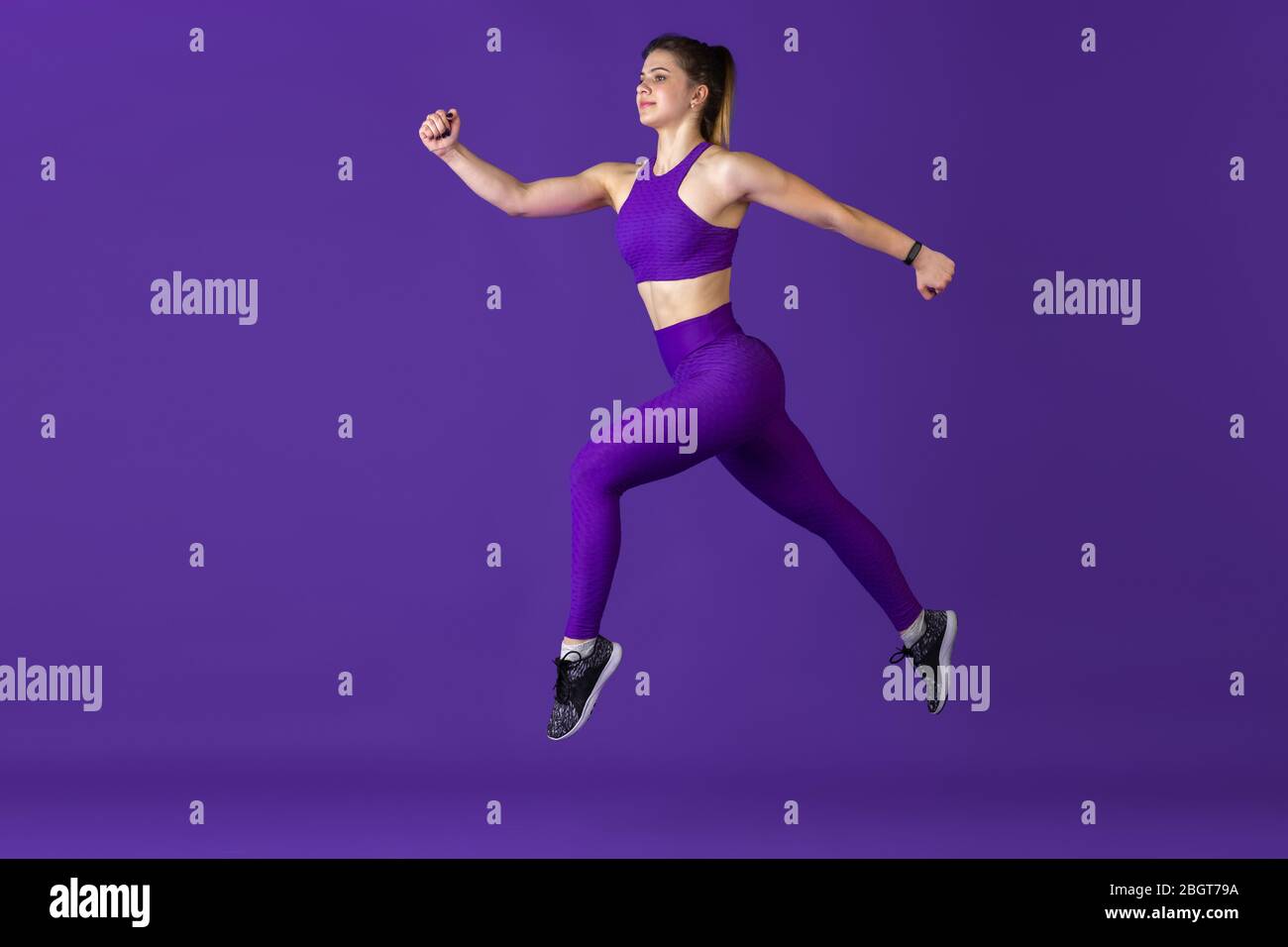 In jump. Beautiful young female athlete practicing in studio ...