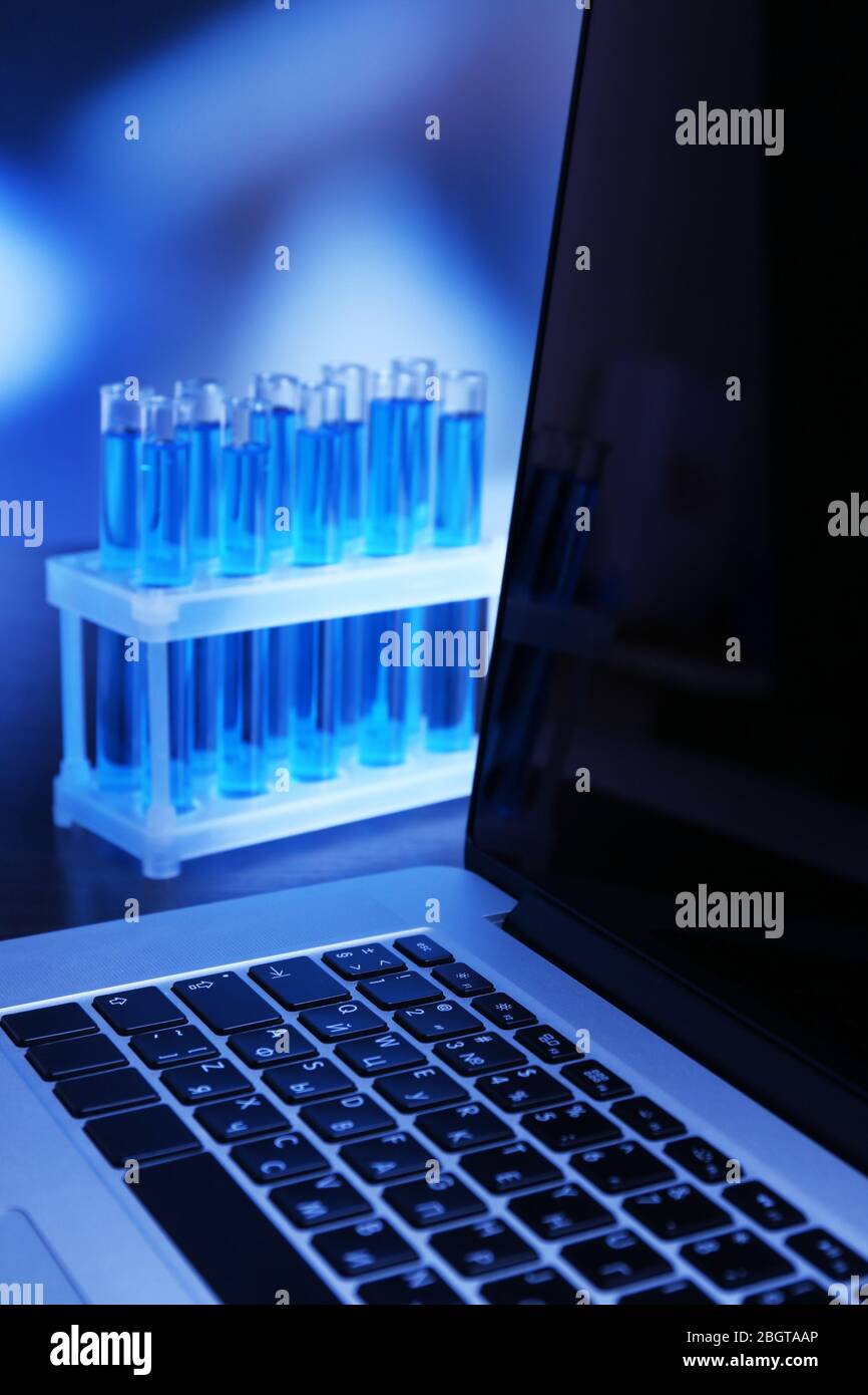 Laptop with test tubes in a laboratory on blue background Stock Photo ...