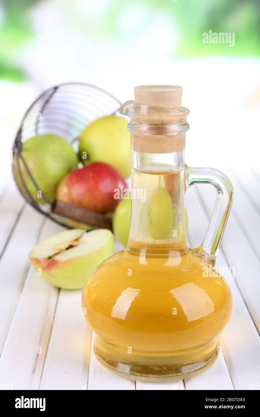Apple cider vinegar in glass bottle and ripe fresh apples, on wooden ...