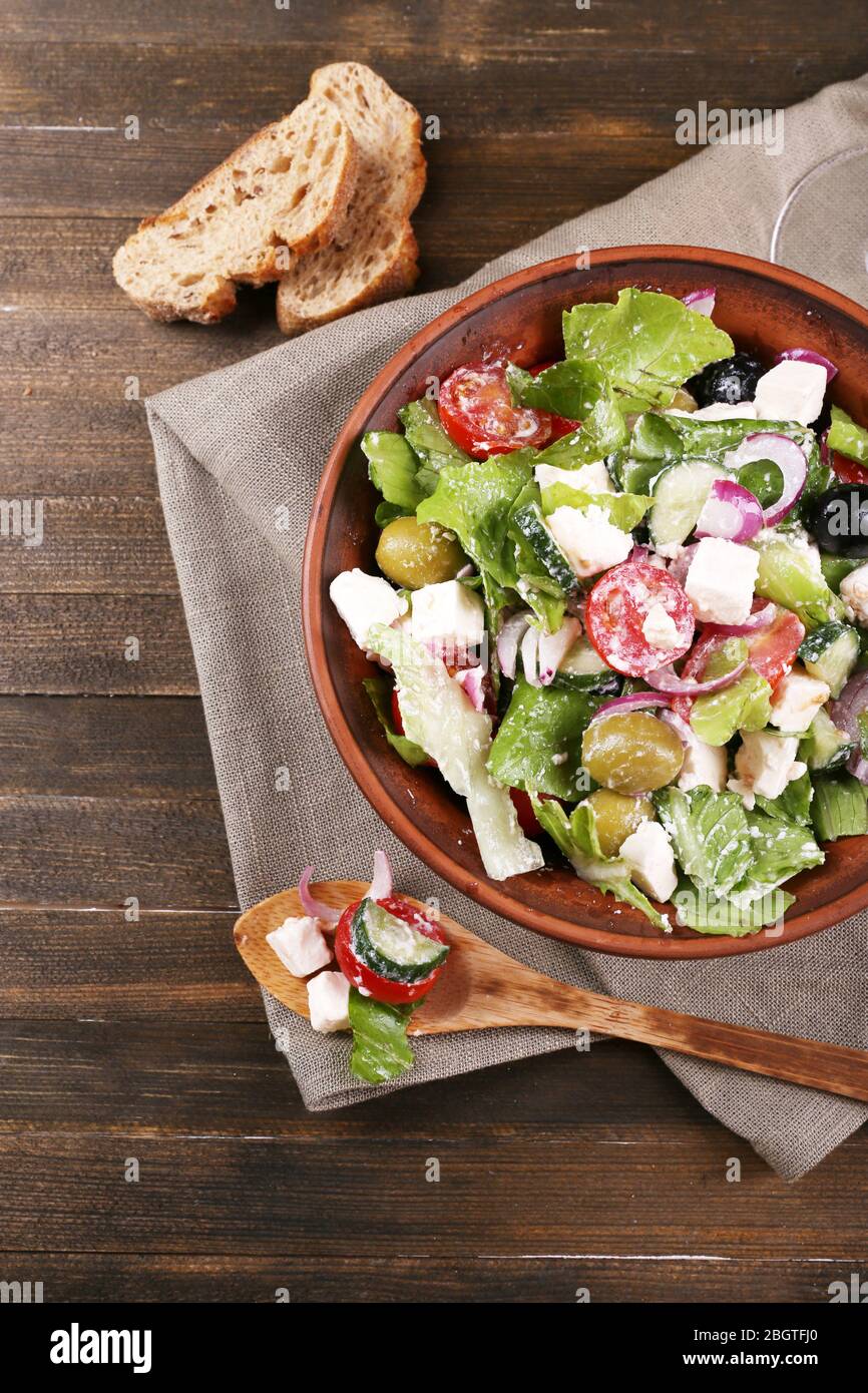 Greek salad served in bowl with slice of bread on sacking napkin on ...