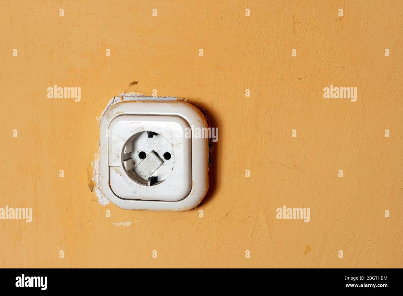 Dirty power outlet on a yellow wall Stock Photo - Alamy