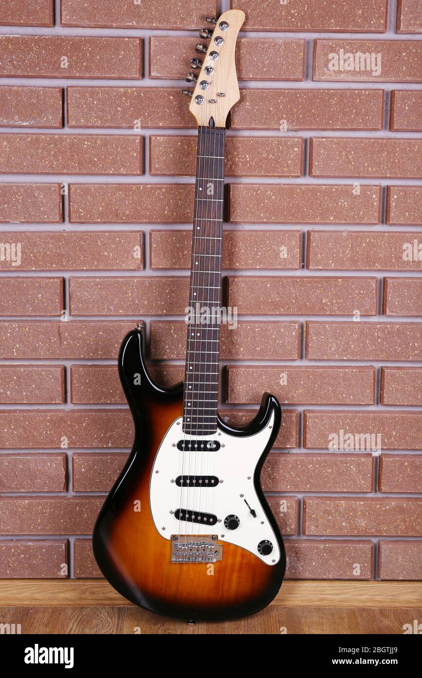 Guitar on brick wall background Stock Photo - Alamy
