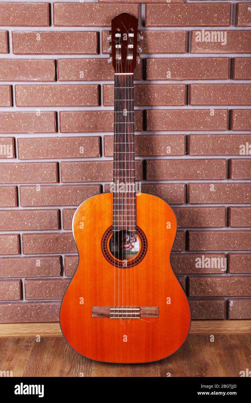 Guitar on brick wall background Stock Photo - Alamy