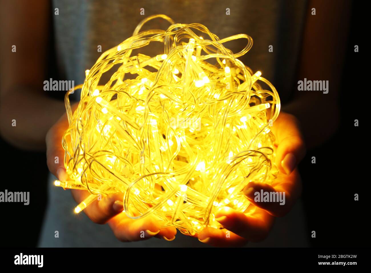 Woman holding yellow garland on dark background Stock Photo - Alamy