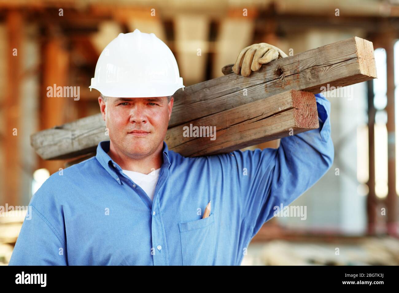 Male construction foreman holding lumber looking at camera Stock Photo ...