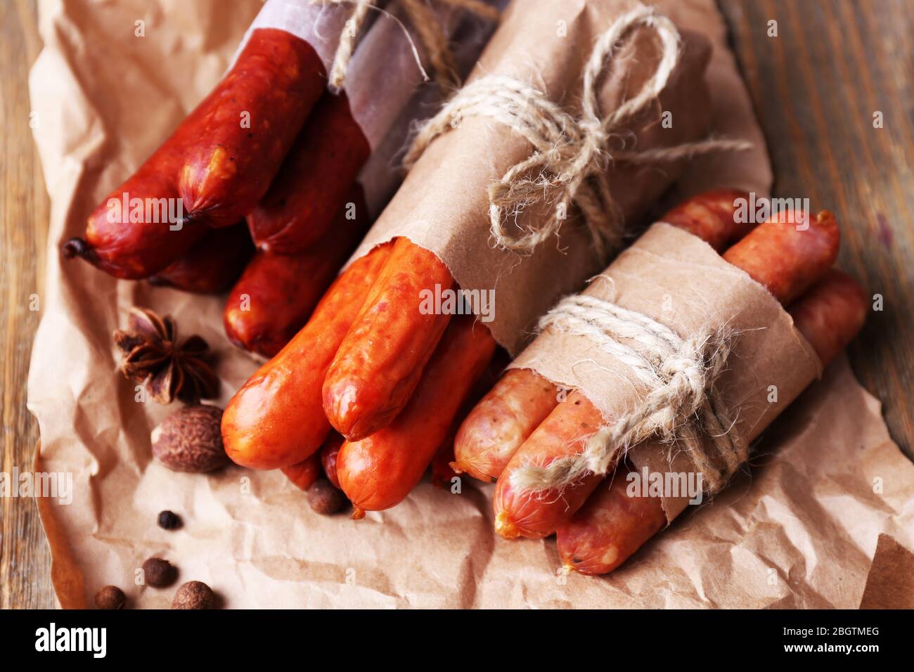 Assortment of thin sausages, and spices on paper, on wooden background ...